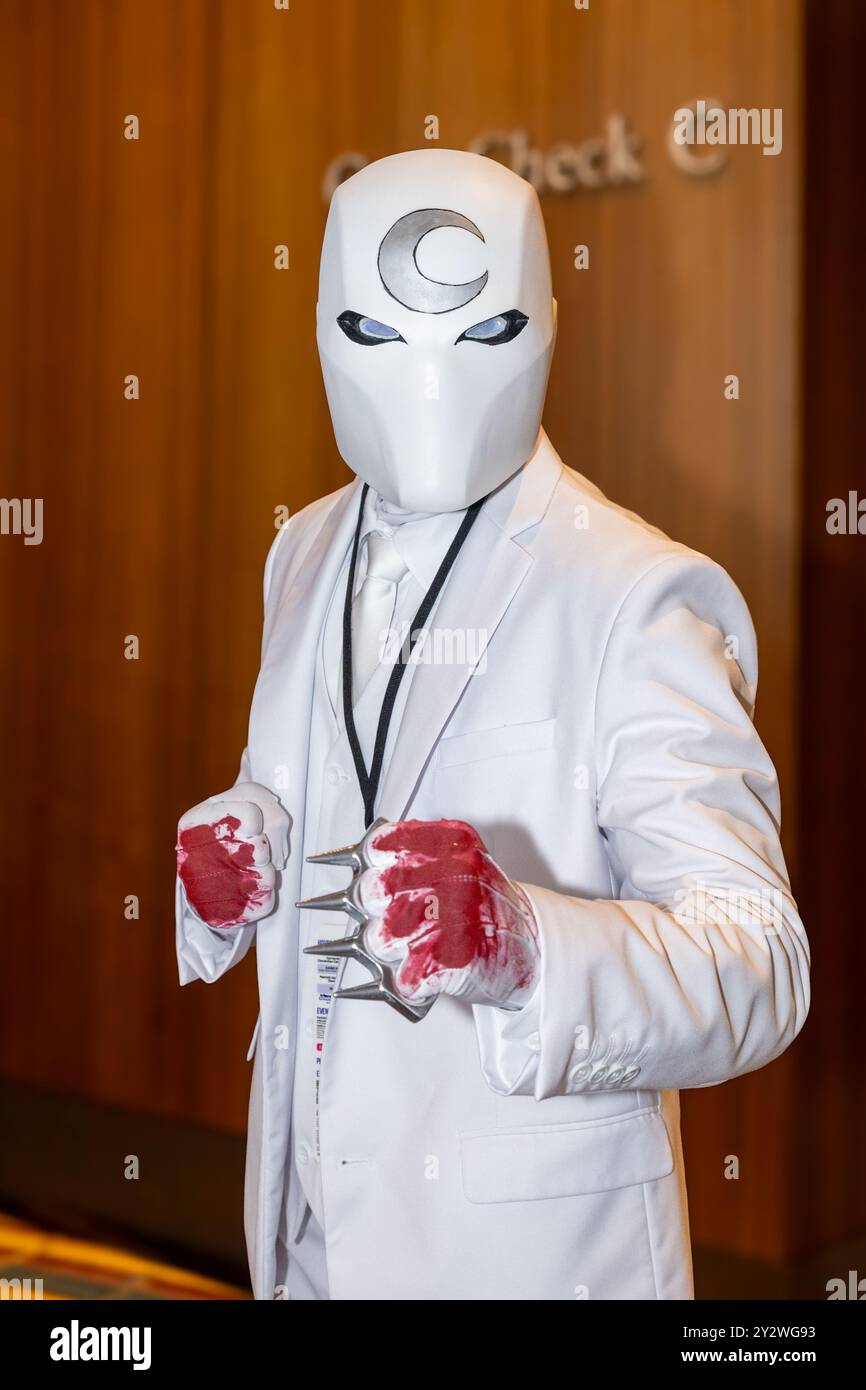 A person in a white costume and mask with a crescent moon symbol as ...