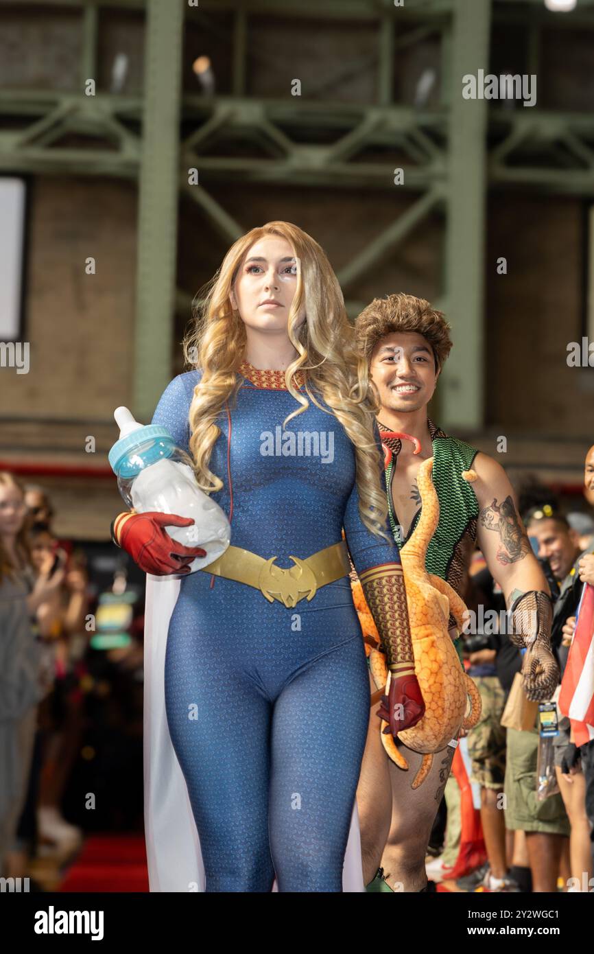 A vertical of cosplayers dressed as superheroes walking on a red carpet at the Brooklyn Comic ...