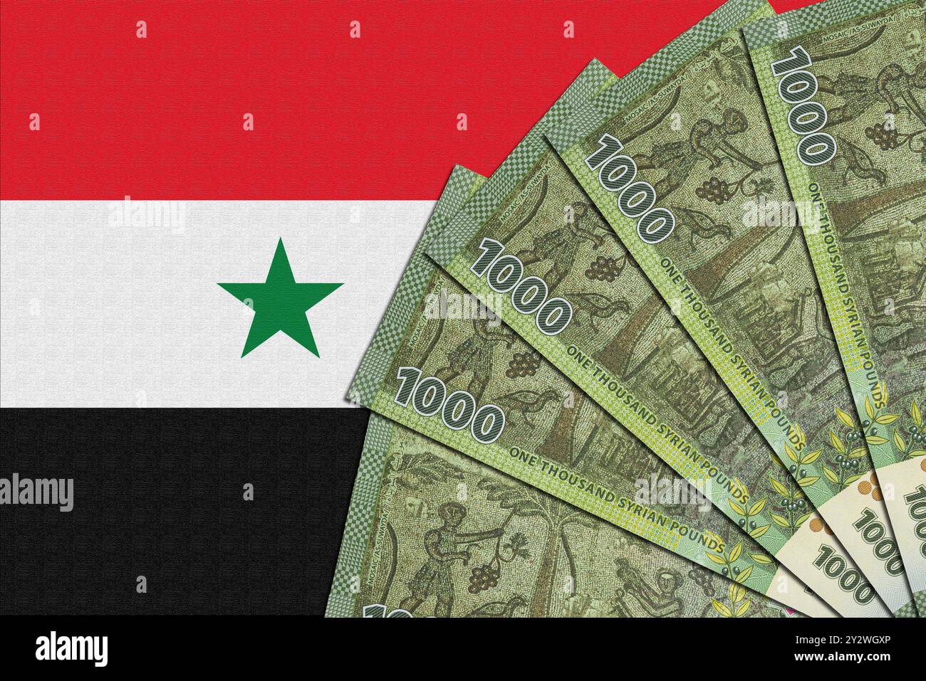 Syrian flag with a fan of 1000 Syrian pound banknotes spread out in the ...