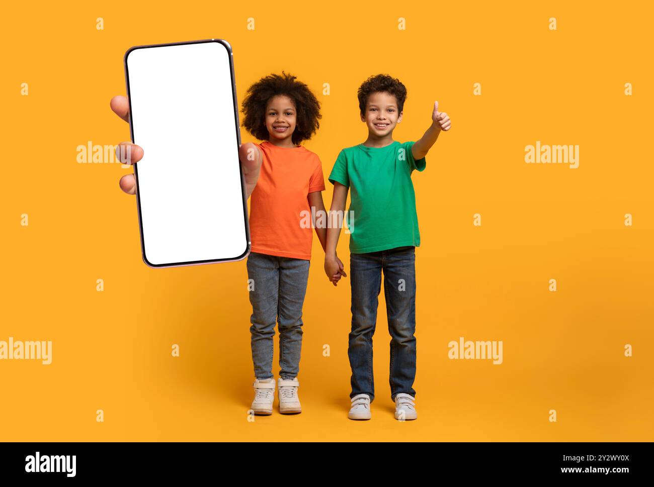 Kids holding hands and posing with a smartphone in a bright setting ...