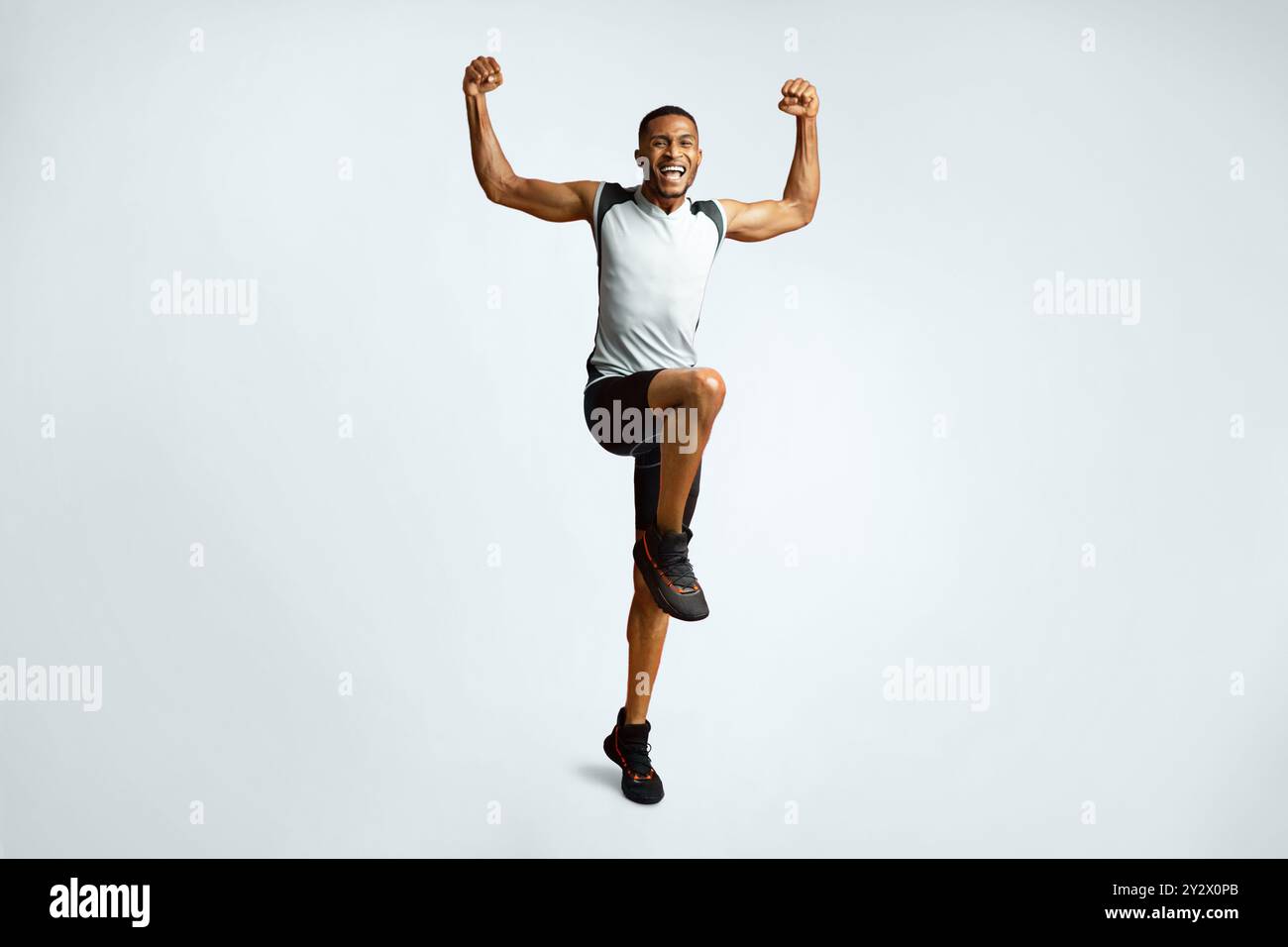 Full length afro guy celebrating triumph jumping at studio Stock Photo ...