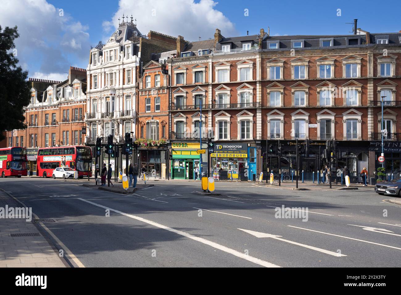 Pedestrians cross at a busy intersection in Putney. Victorian-era ...