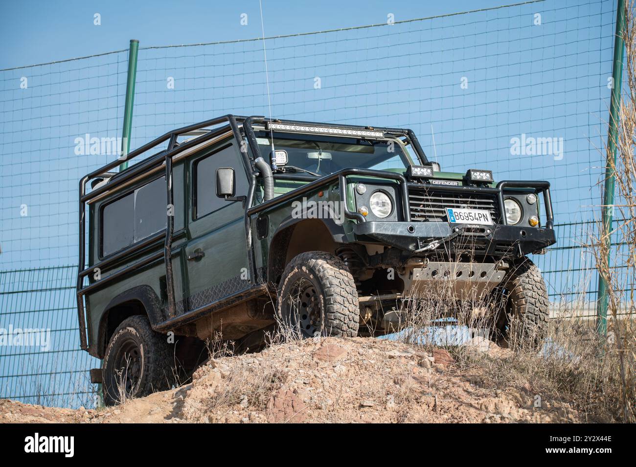 A short green Land Rover Defender with roll bars and winch at the top ...