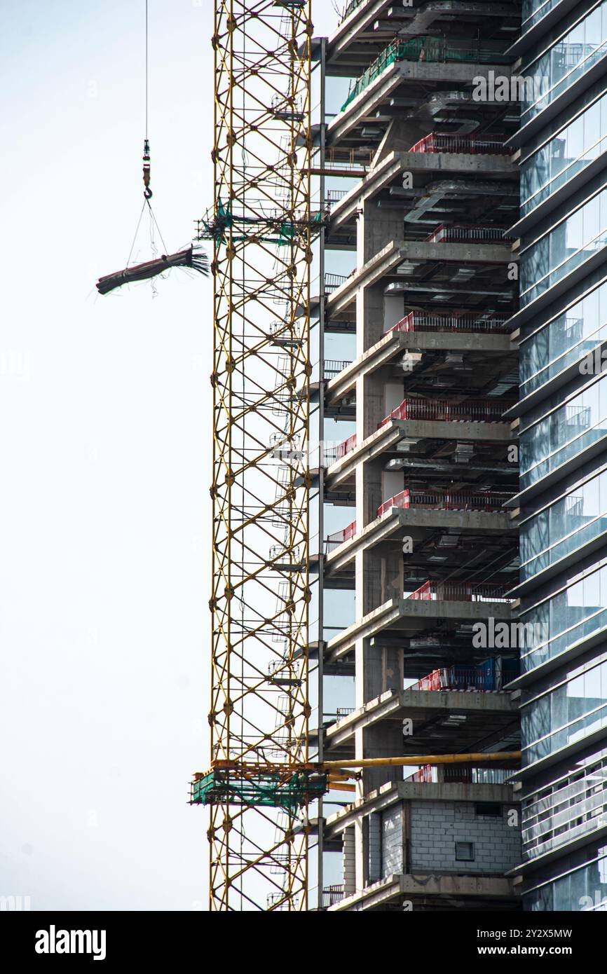 A high-rise building under construction with a crane lifting materials ...