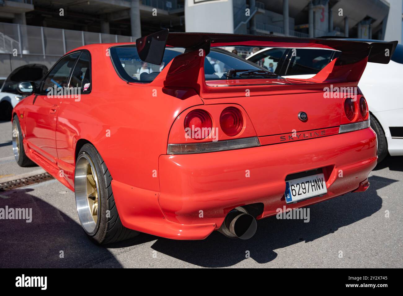 Rear view of a red ninth-generation Nissan Skyline GTR-R33 at a ...