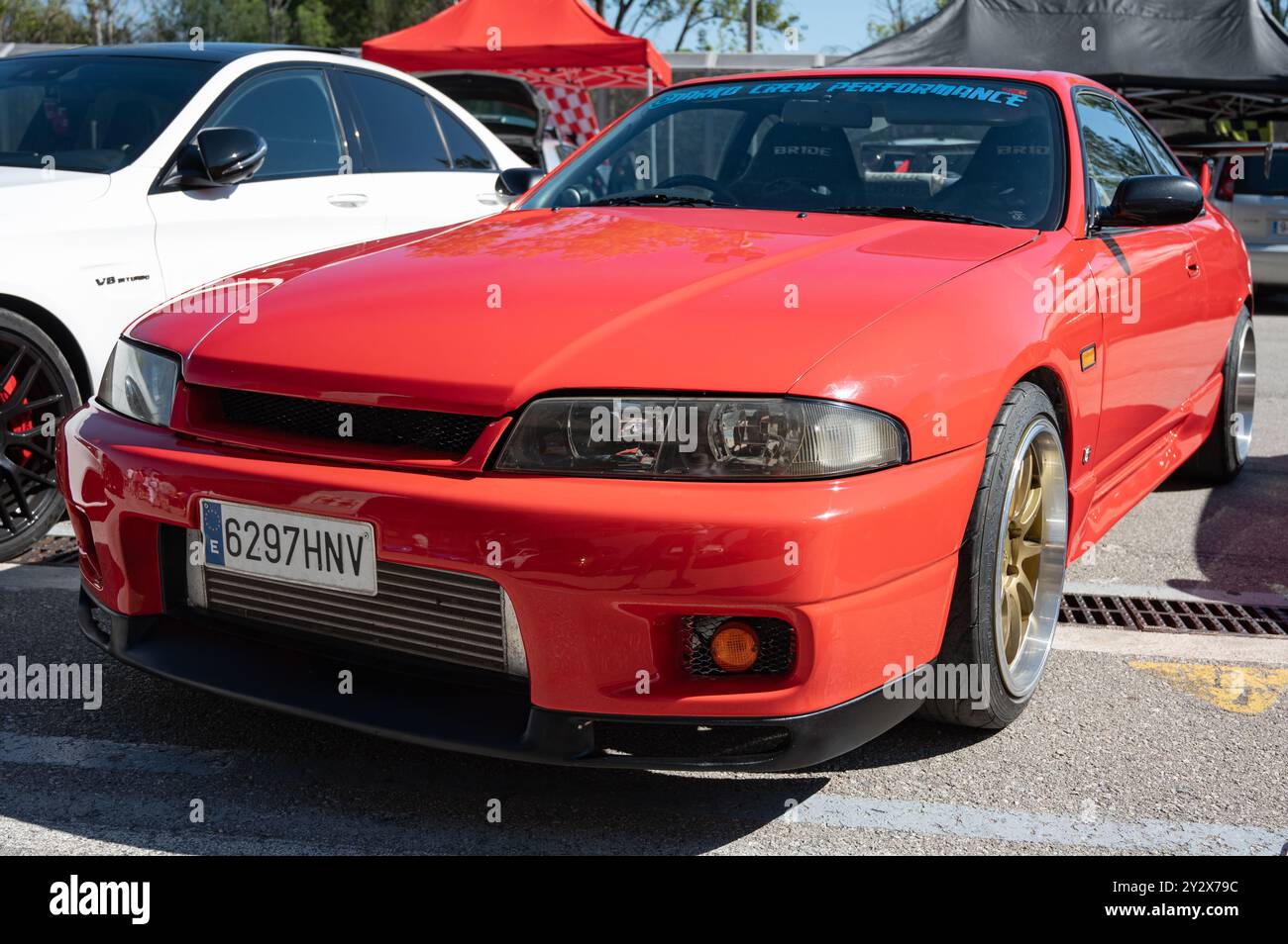 Front view of a red ninth-generation Nissan Skyline GTR-R33 at a Japanese sports car meet Stock ...