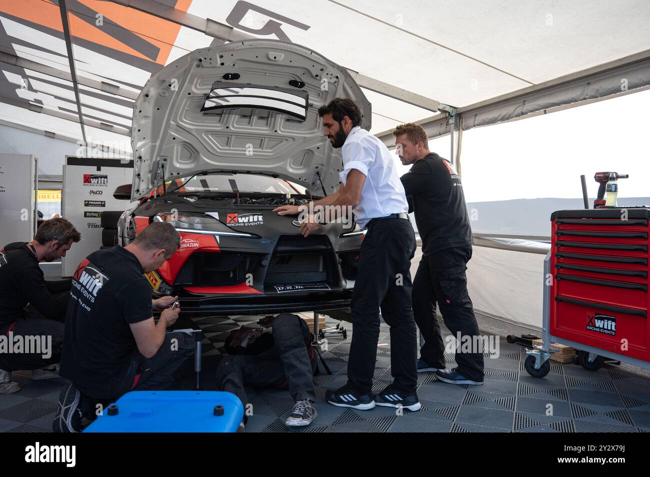 Pit tent of a GT4 European Series racing team. The mechanics are tuning ...