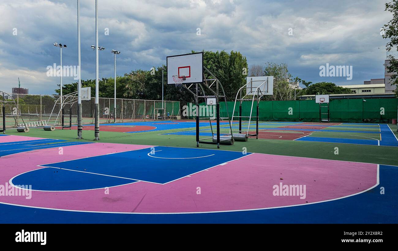 A colorful outdoor basketball court with multiple hoops under a cloudy ...