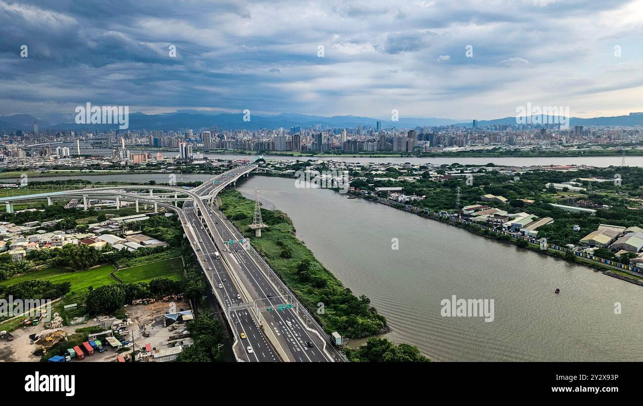 Aerial view of a cityscape with a river and highway under a cloudy sky ...