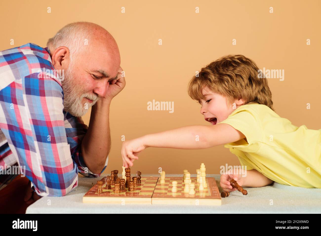 Grandfather and grandson playing chess together. Grandpa teaching ...