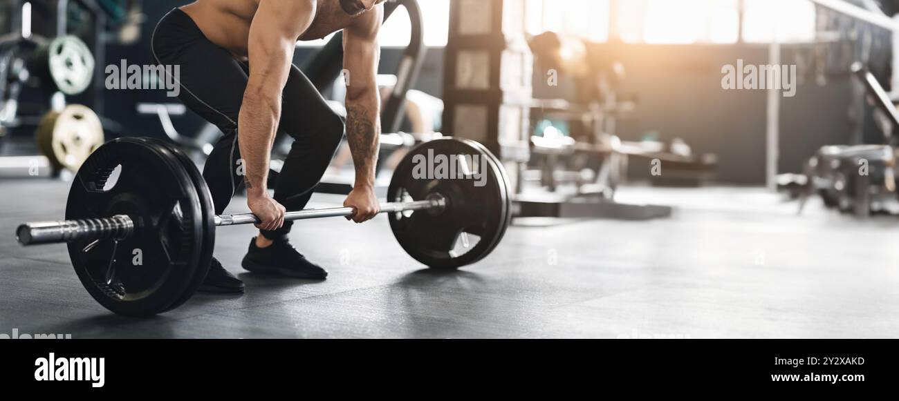 Muscular powerlifter lifting heavy barbell from gym floor Stock Photo ...