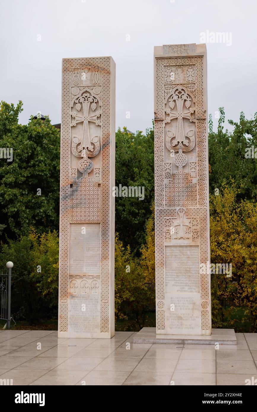 A vertical view of two cross-stones with religious carvings including ...