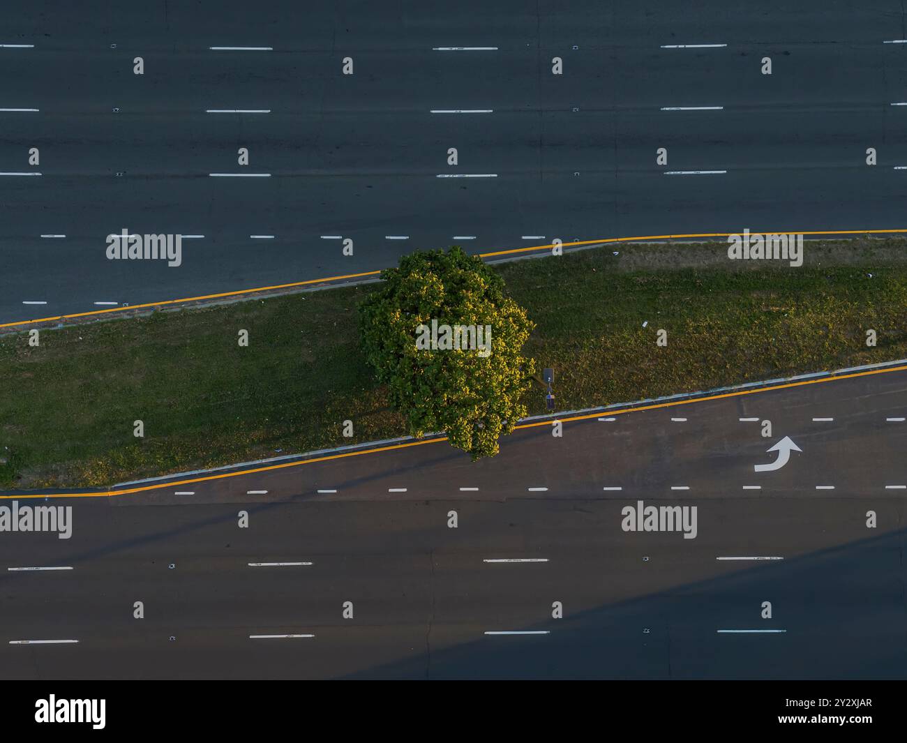 An aerial view of an empty highway with a green grass median and a ...