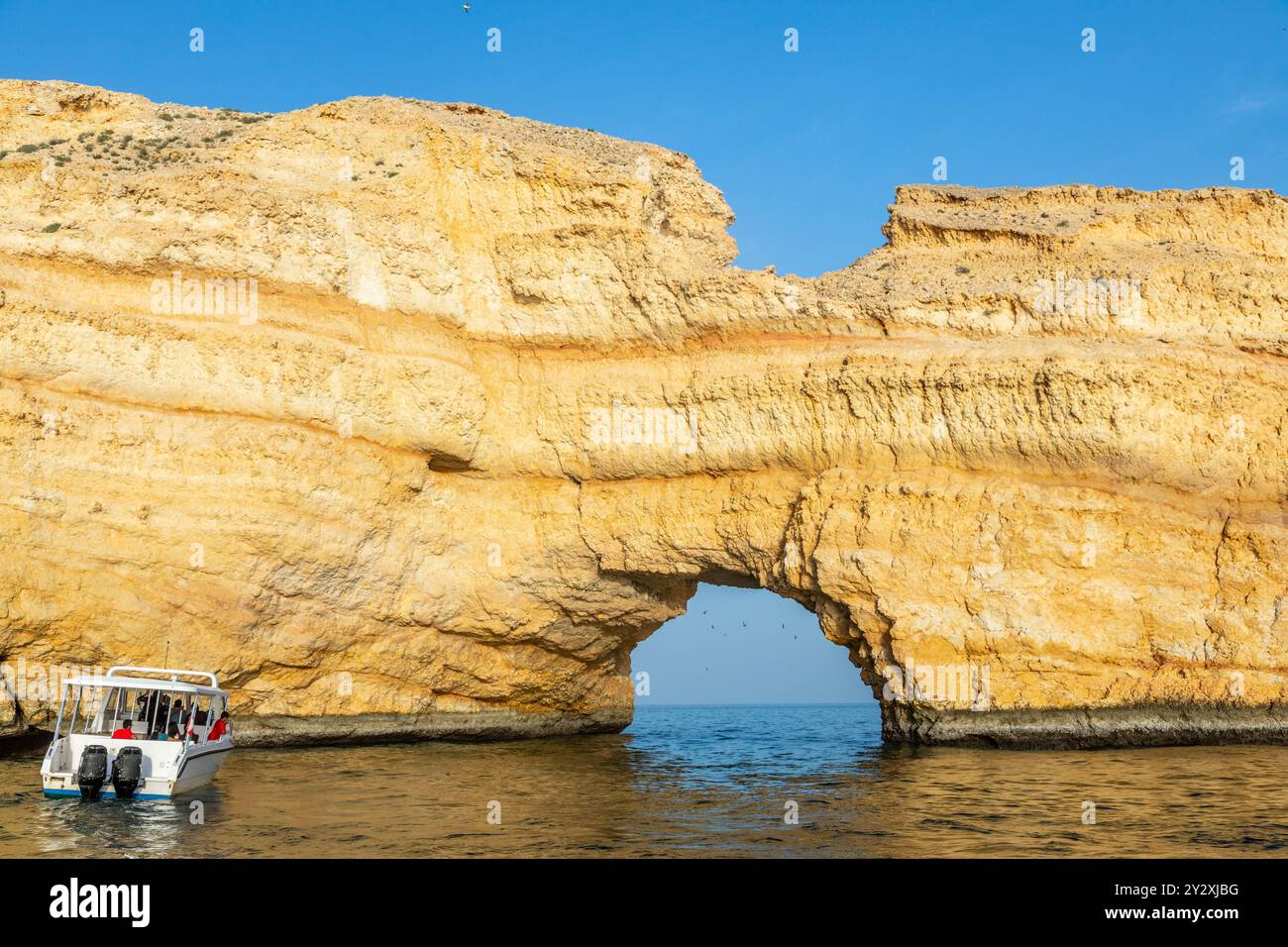Qantab natural arch passage in the rock and boat full of tourists ...