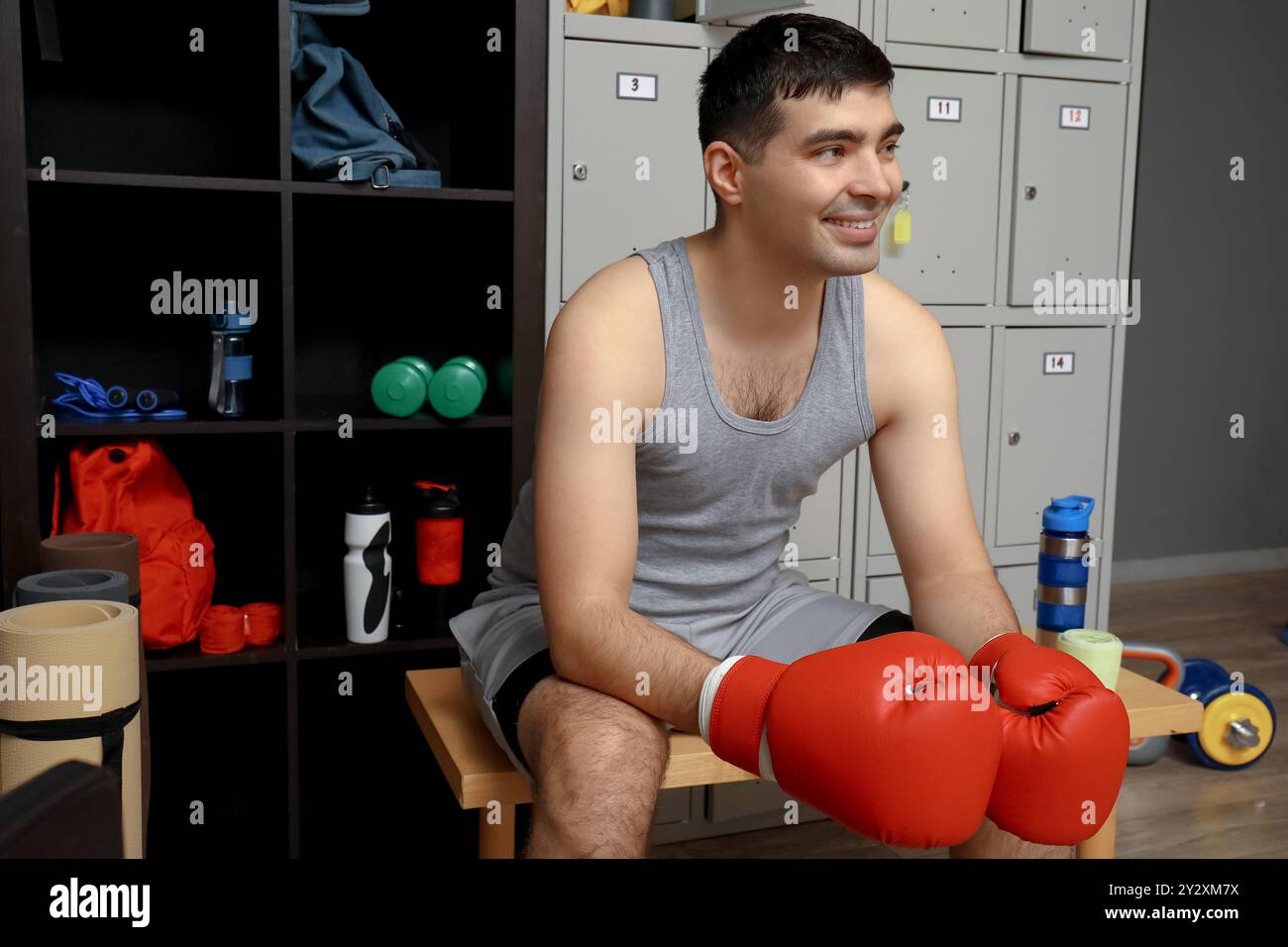 Sporty young man with boxing gloves near locker in changing room Stock ...
