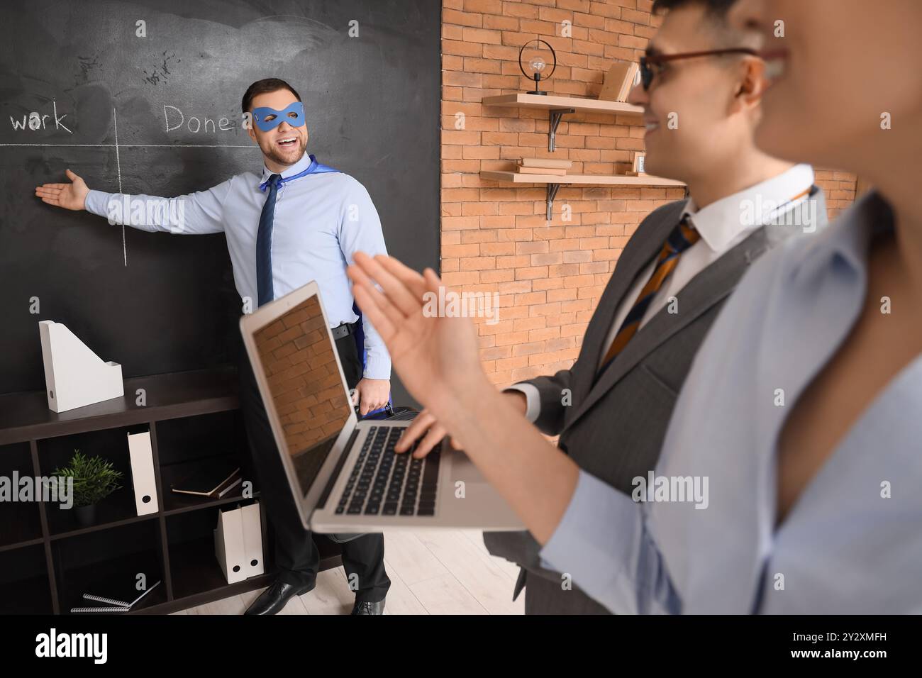 Business man dressed as superhero giving presentation to his colleagues ...