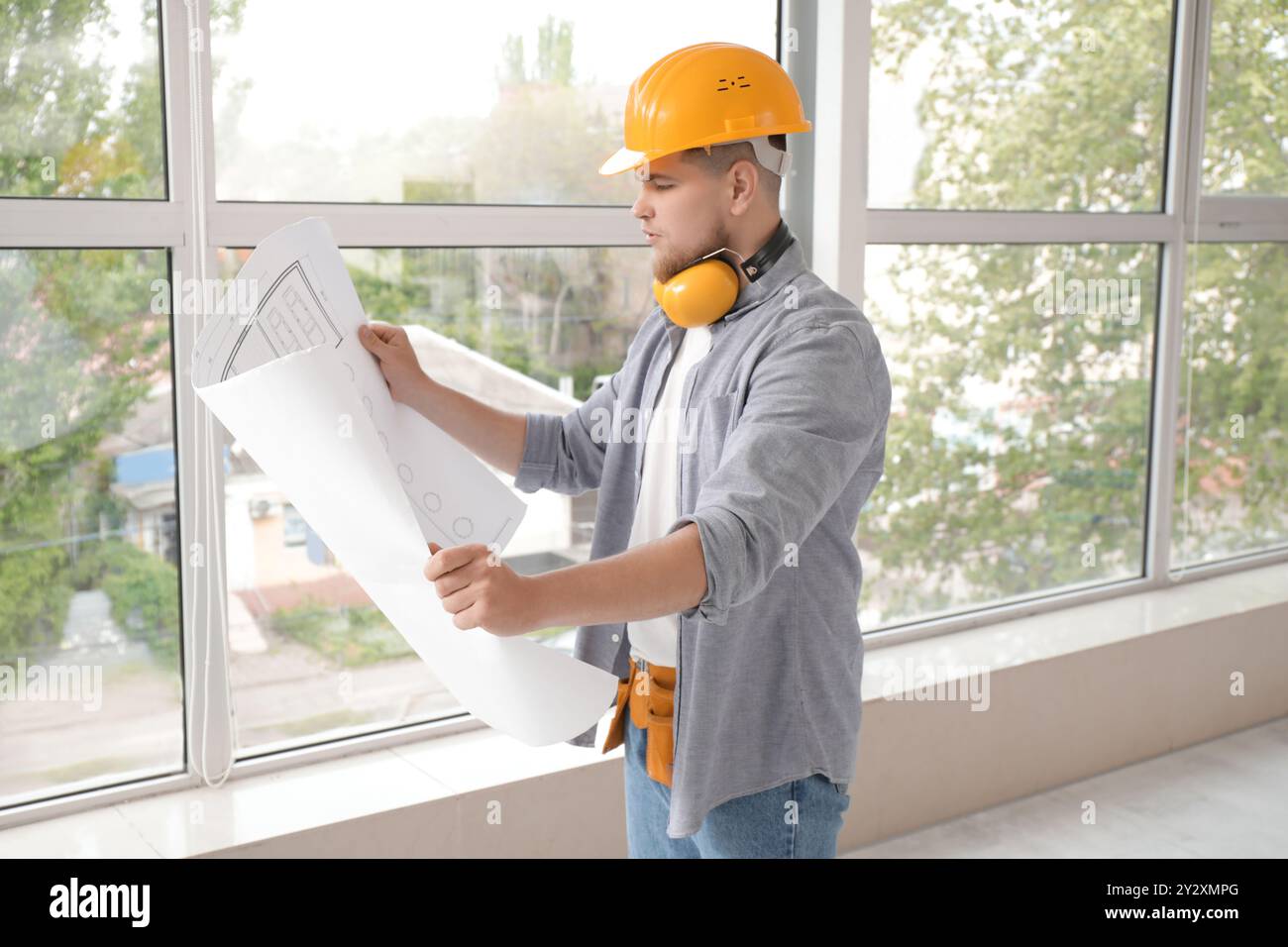Male contractor with house plan near window in room Stock Photo - Alamy