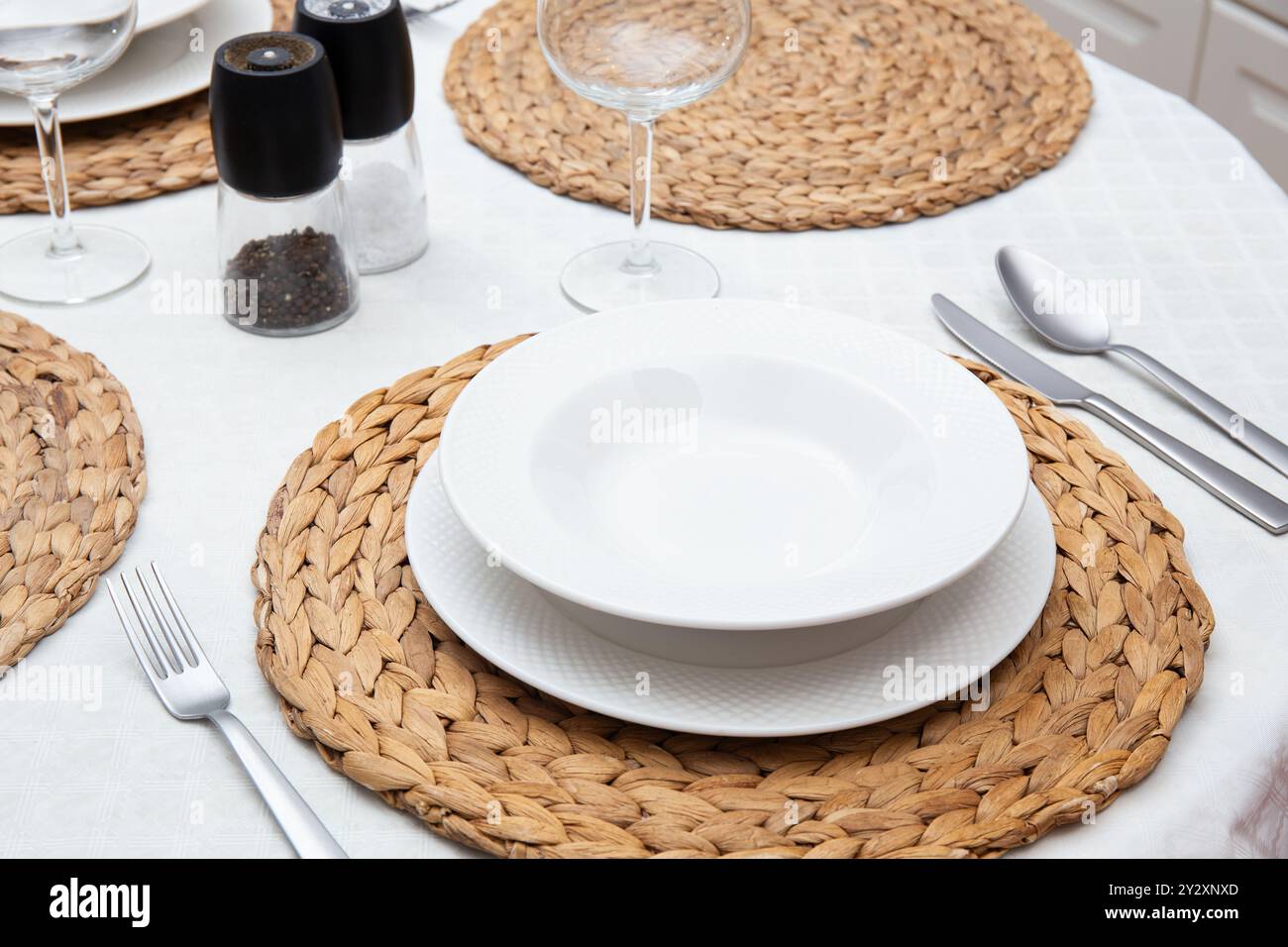 Set table in restaurant, featuring white plates, woven placemats ...