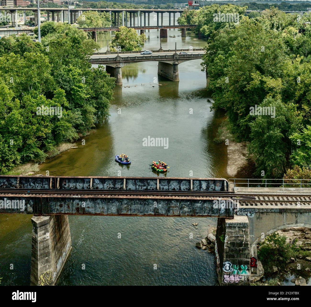 Aerial view of people rafting on a river surrounded by lush green trees ...