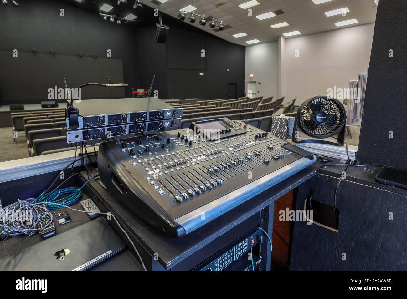 A modern audio mixing console setup in an empty auditorium with rows of ...
