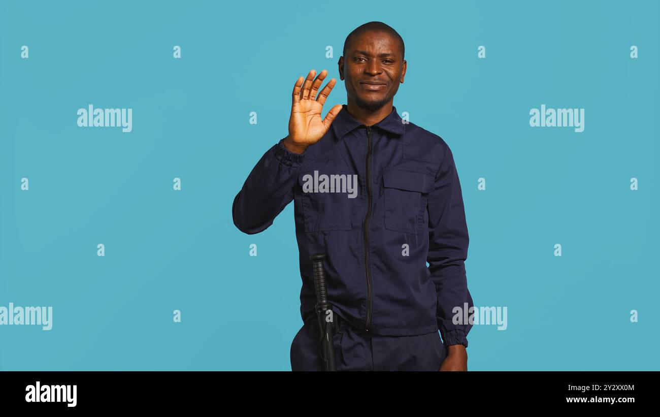 Smiling security guard saluting people during surveillance shift ...