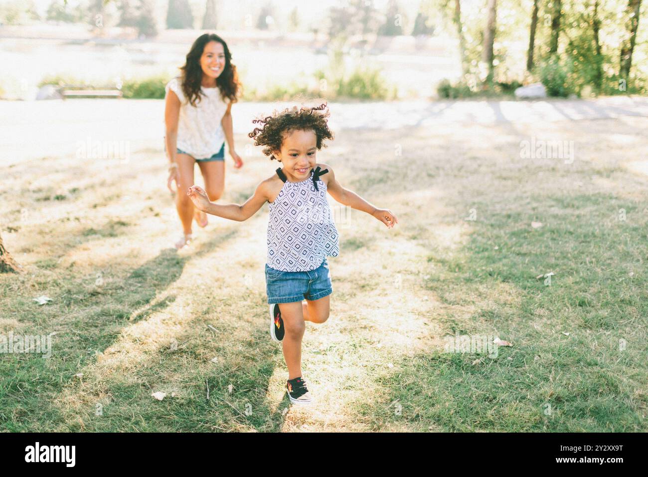A happy mother chasing her daughter in a field Stock Photo - Alamy