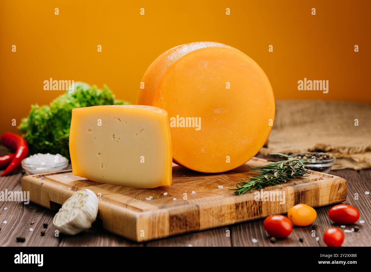 Golden cheese wheel and slice on wooden board, ideal for food ...