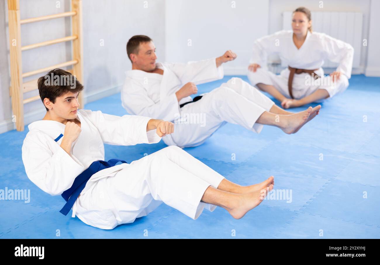 Woman and men in kimono train abdominal muscles and do punches at same ...