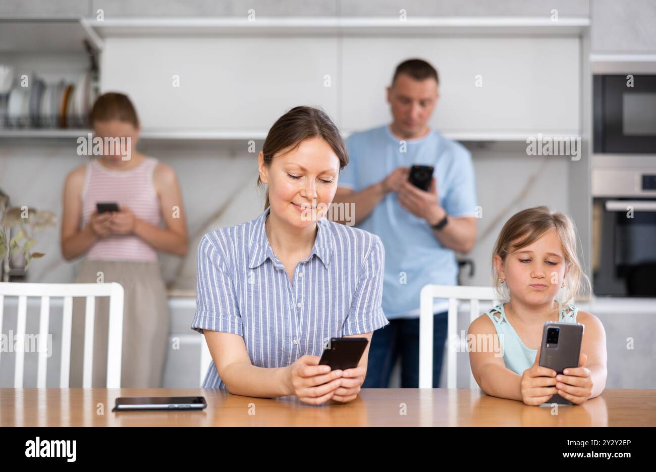 Tween girl with mother absorbedly staring at screens of smartphones in ...