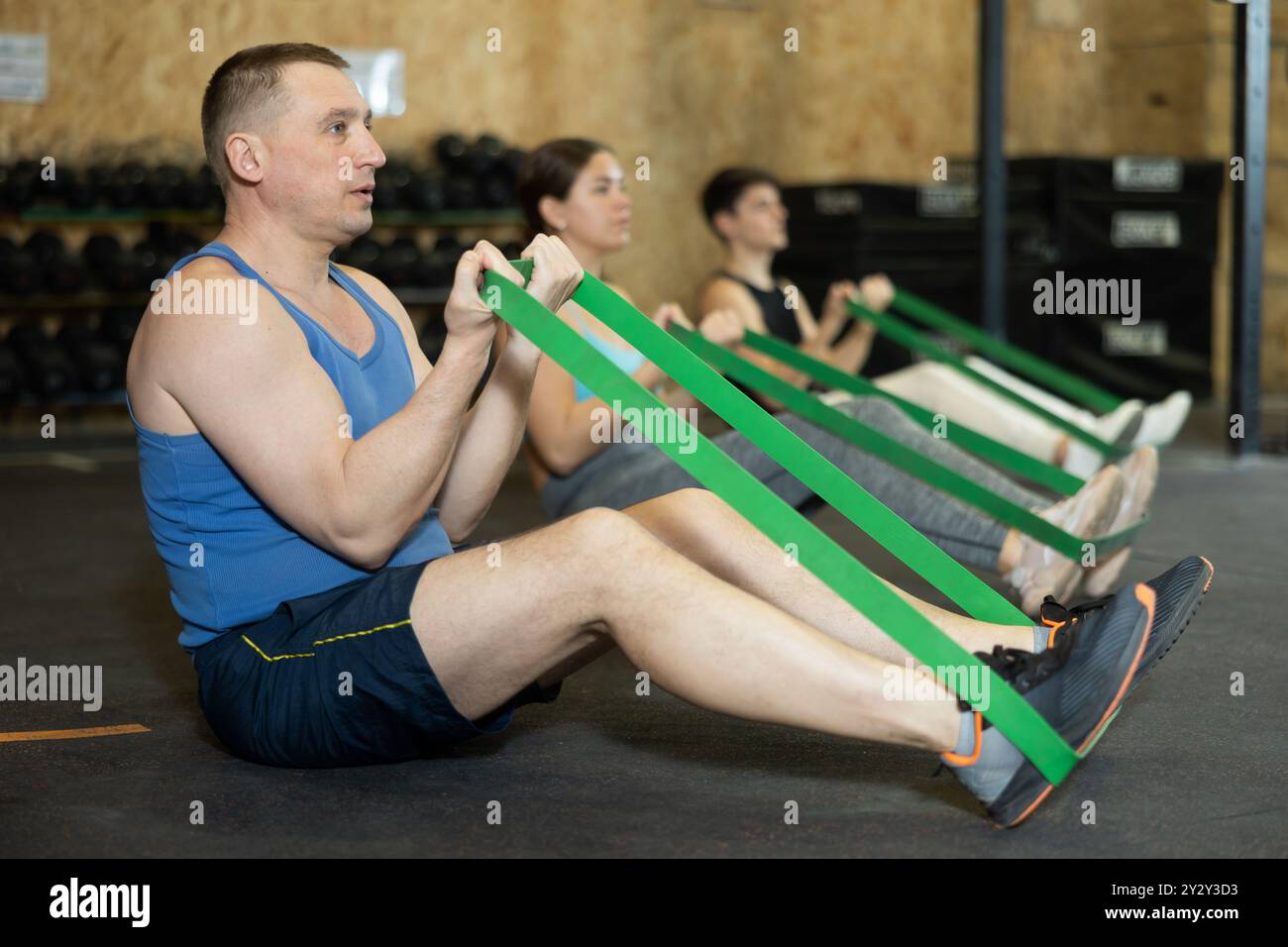 Active middle-aged man wearing sport clothes using resistance band ...