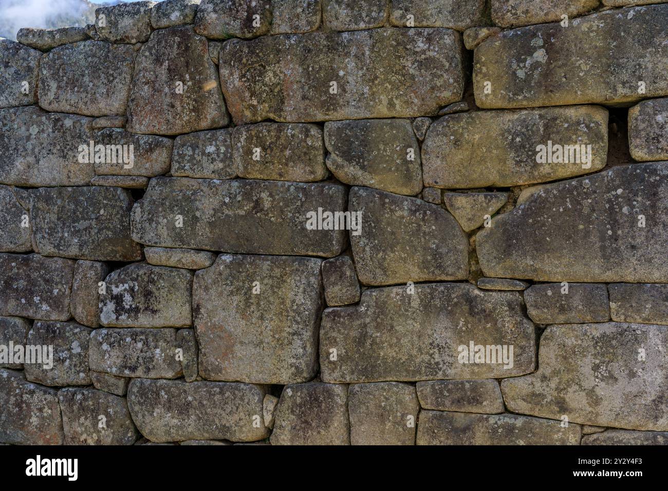 Close-up of an ancient stone wall with weathered textures and moss ...