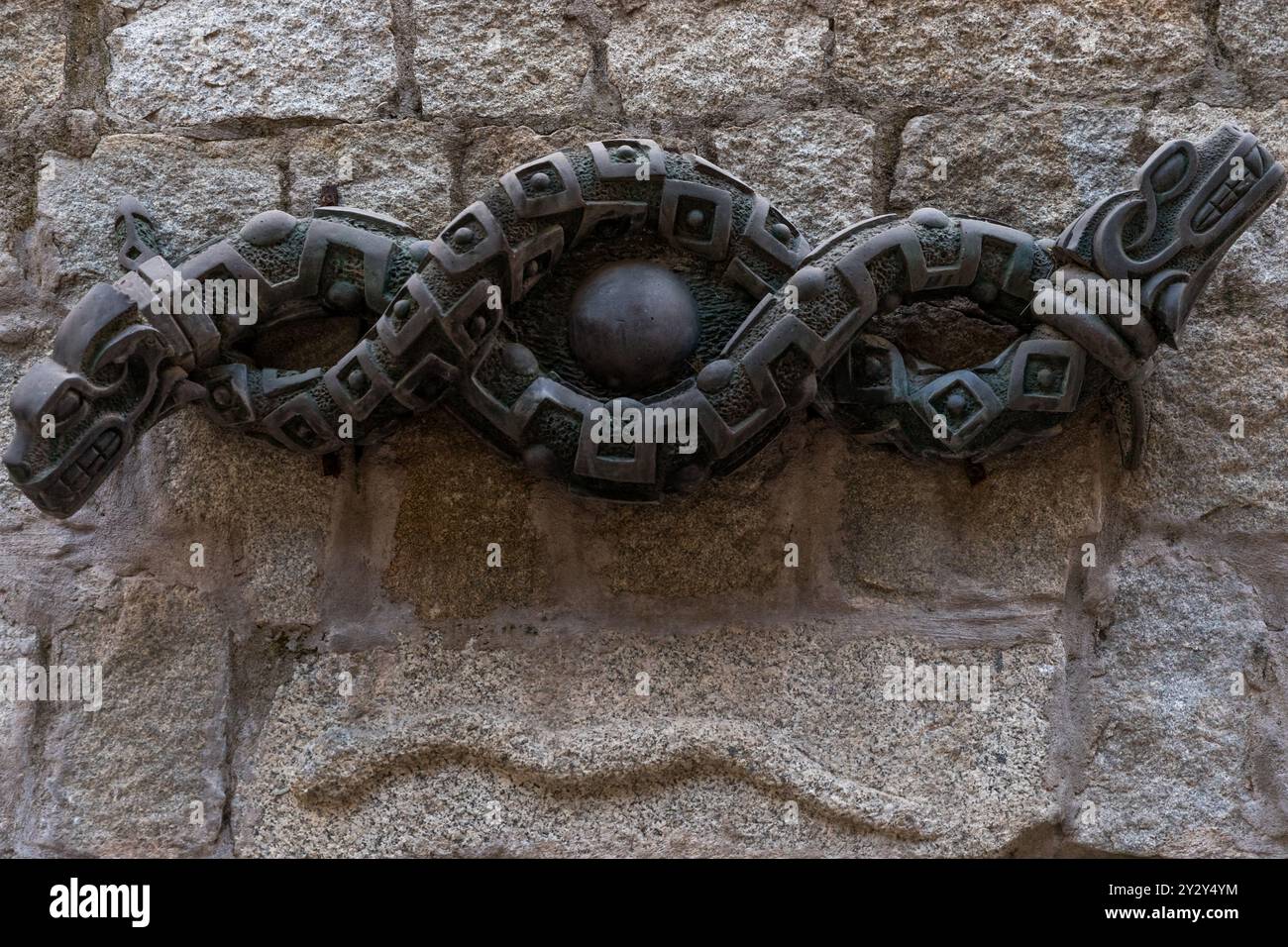Close-up of an ancient stone carving of a serpent on a textured brick ...