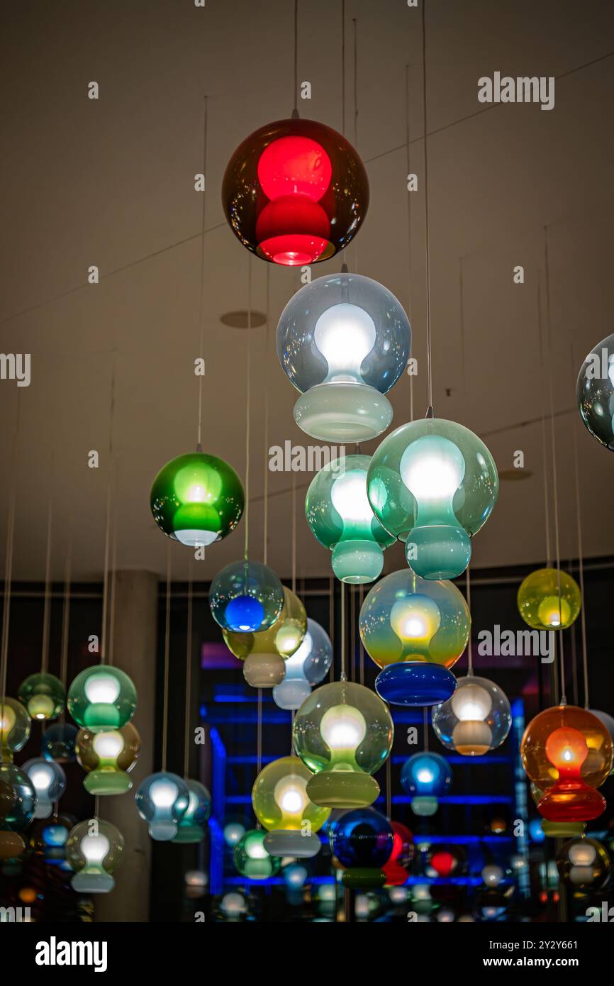 Colorful modern pendant lights hanging from the ceiling in a ...