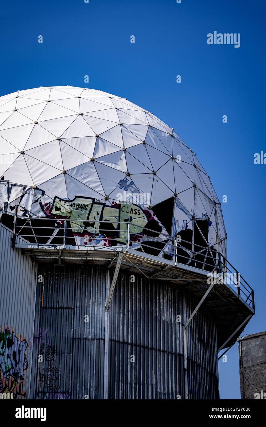 Abandoned radar dome with graffiti under clear blue sky, showcasing ...