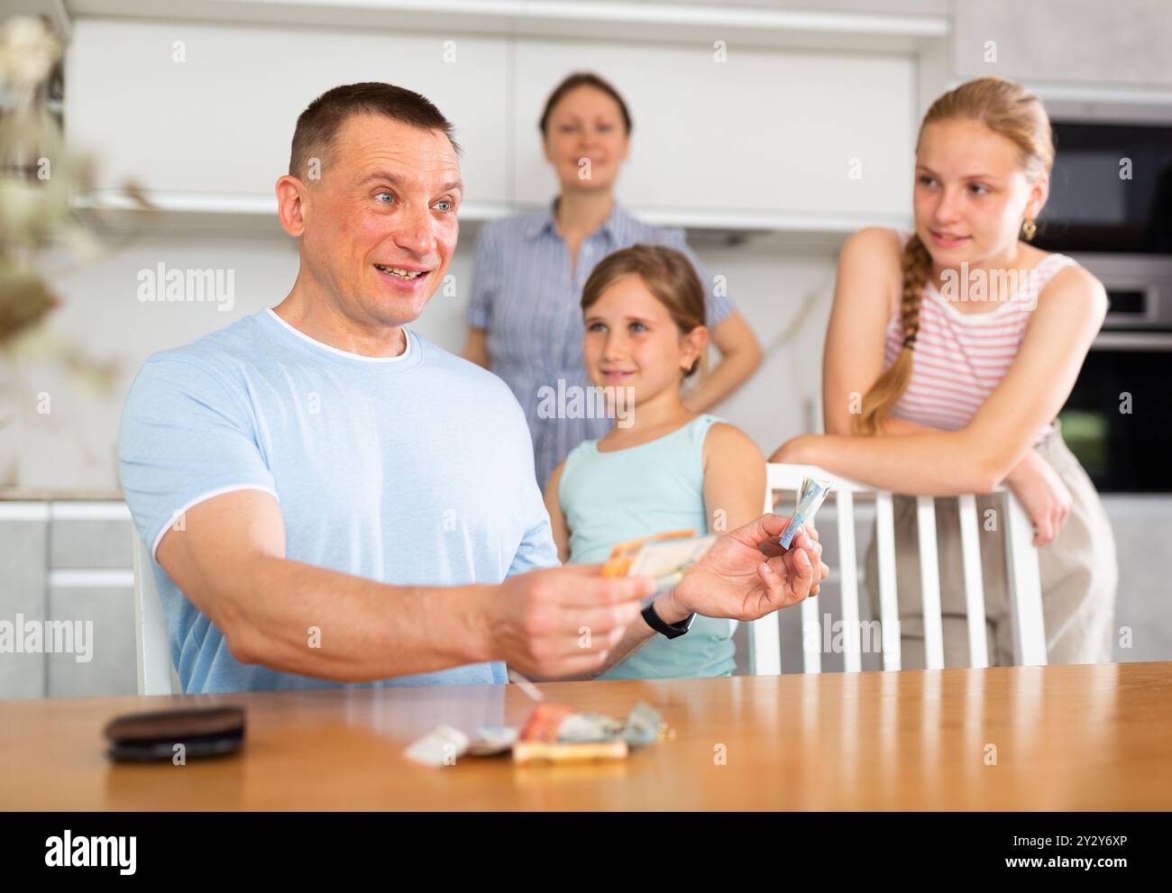 Father gives pocket money to children and wife in kitchen Stock Photo ...