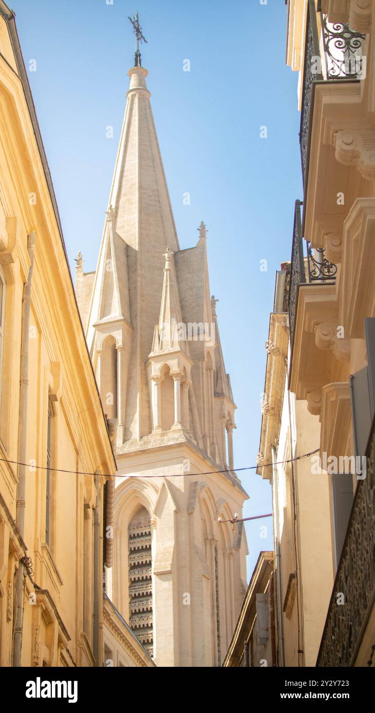 A tall church spire viewed from a narrow street with buildings on both ...