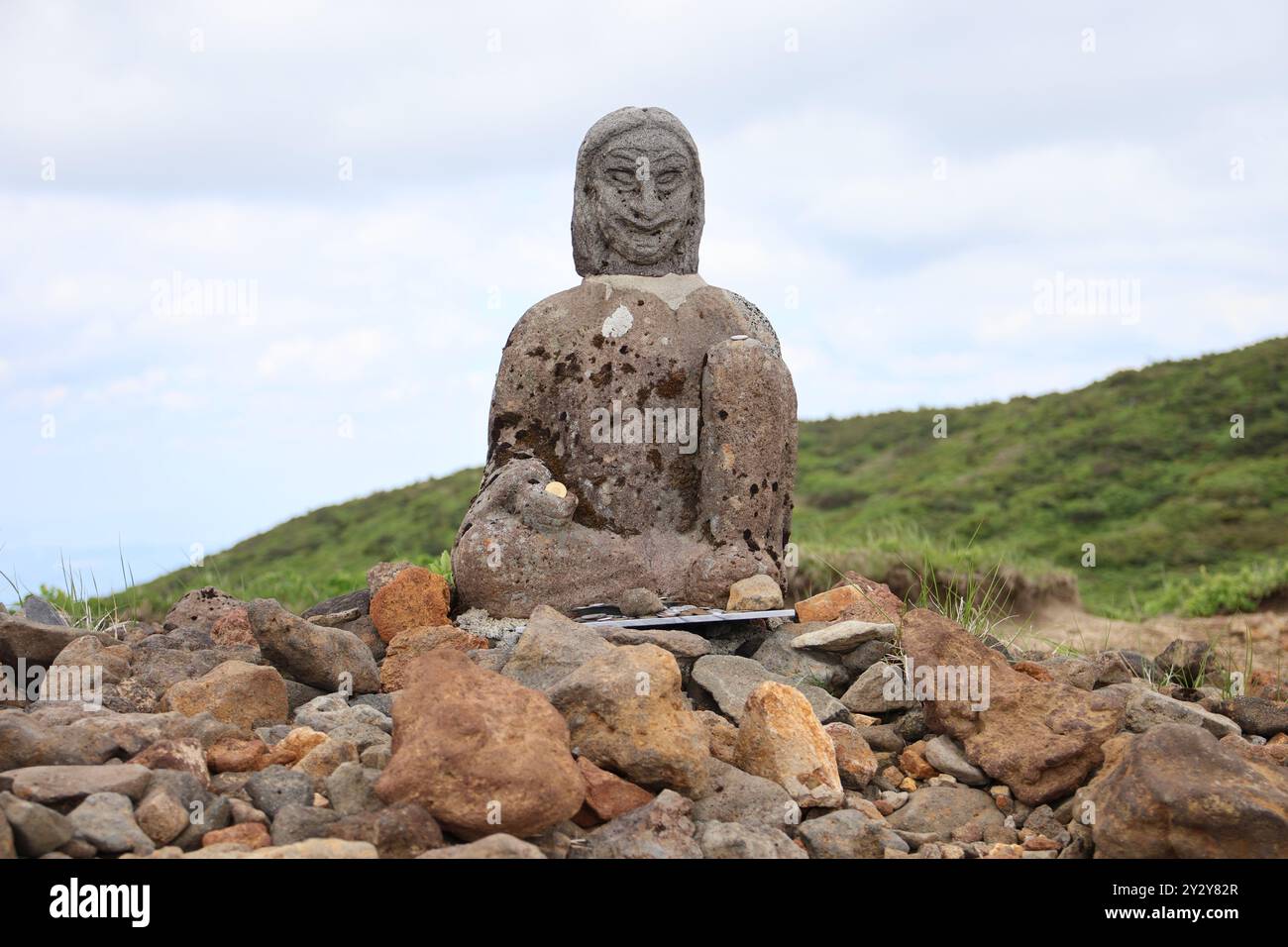 An ancient stone statue of a seated figure surrounded by rocks under a ...