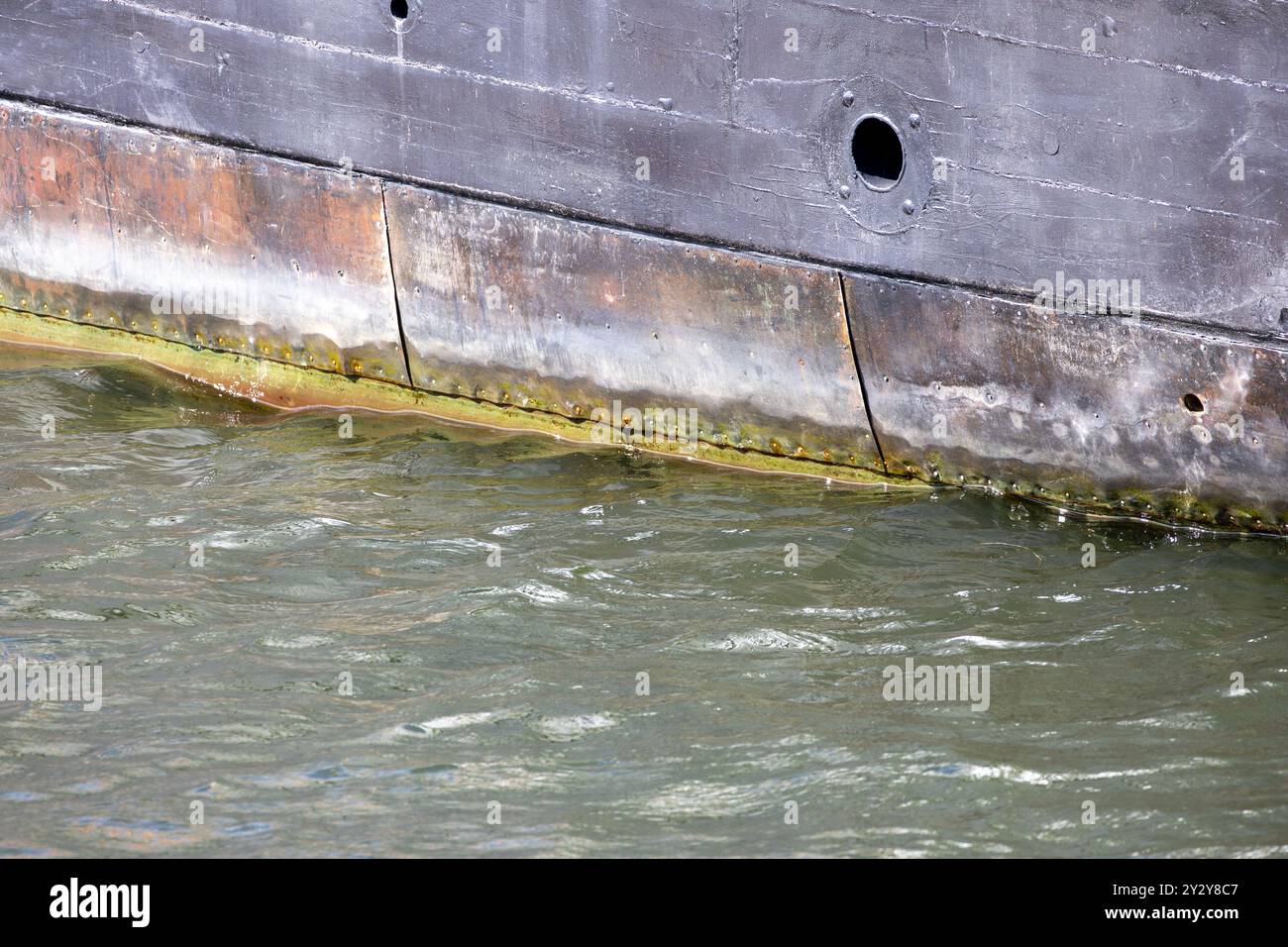 Close-up of a ship's hull submerged in water, showing rust and algae ...