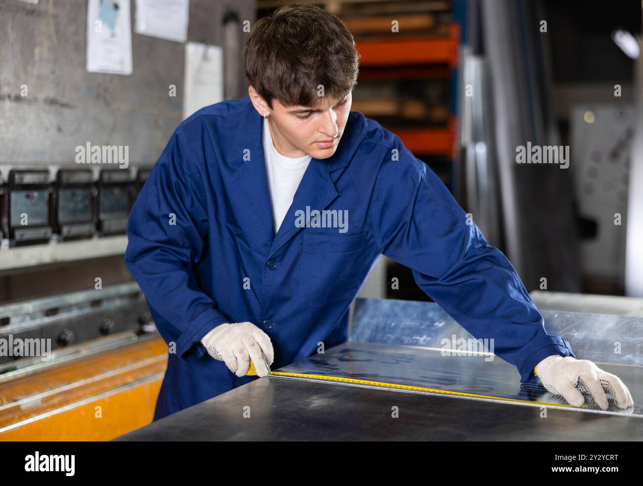 Guy measuring sheet of metal with tape measure Stock Photo - Alamy