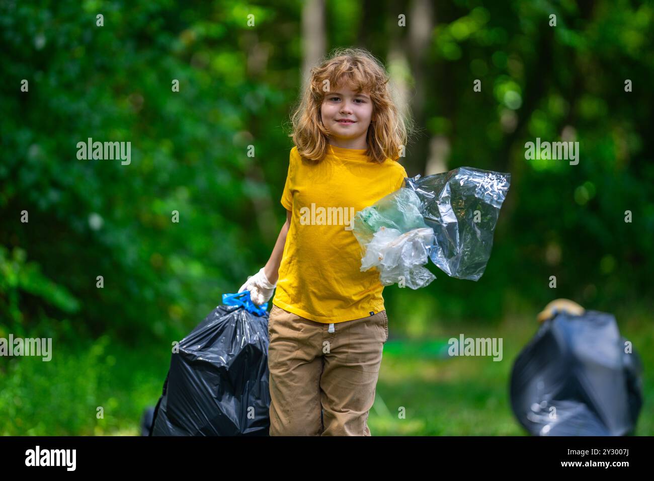 Kid in rubber gloves with trash bag clean up garbage on forest outdoor ...