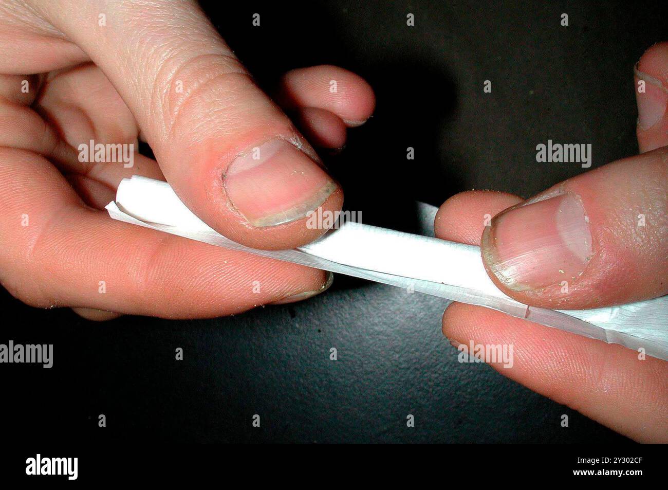 a person smoking a joint, blurred green meadow and blue sky in the back ...