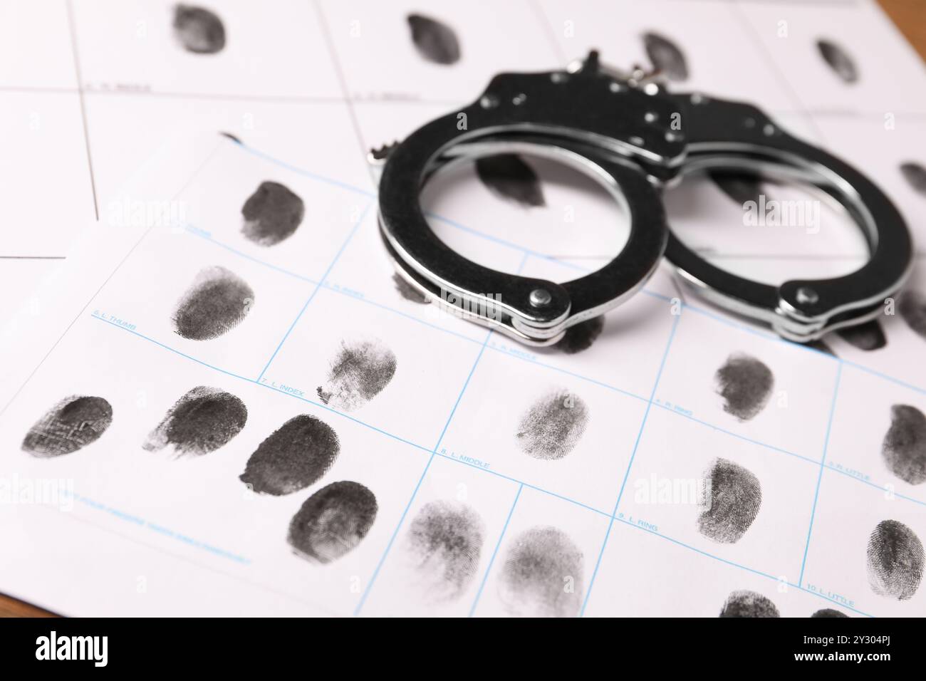 Human fingerprints and handcuffs on paper, closeup. Criminal conviction ...
