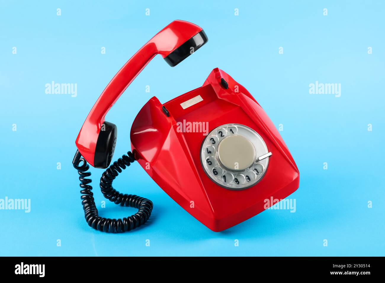 Red telephone with handset on light blue background Stock Photo - Alamy