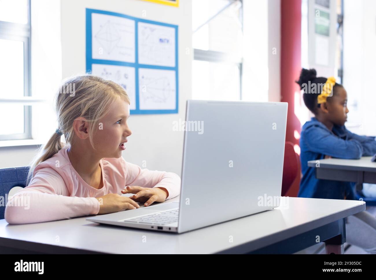 In school, girl using laptop in classroom, focusing on learning ...