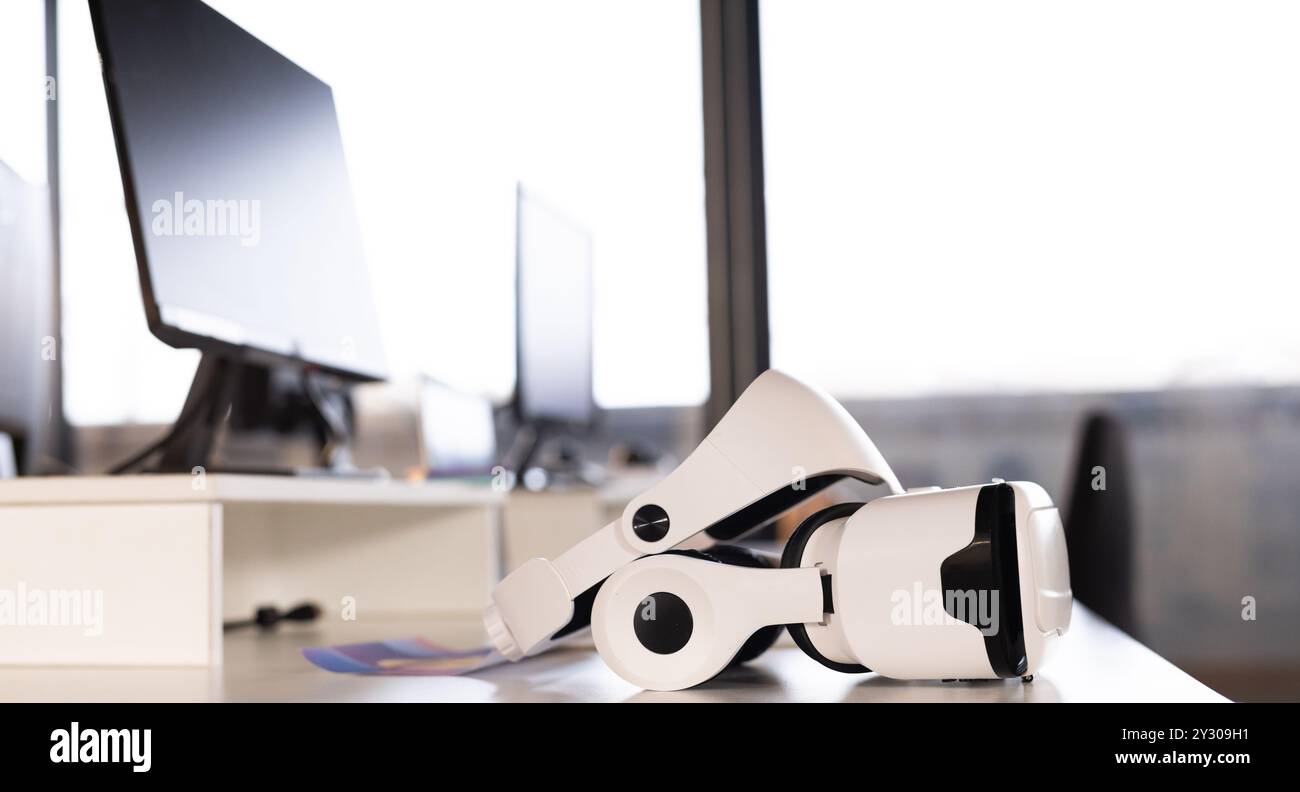 VR headset on desk in modern office with computers, ready for creative ...