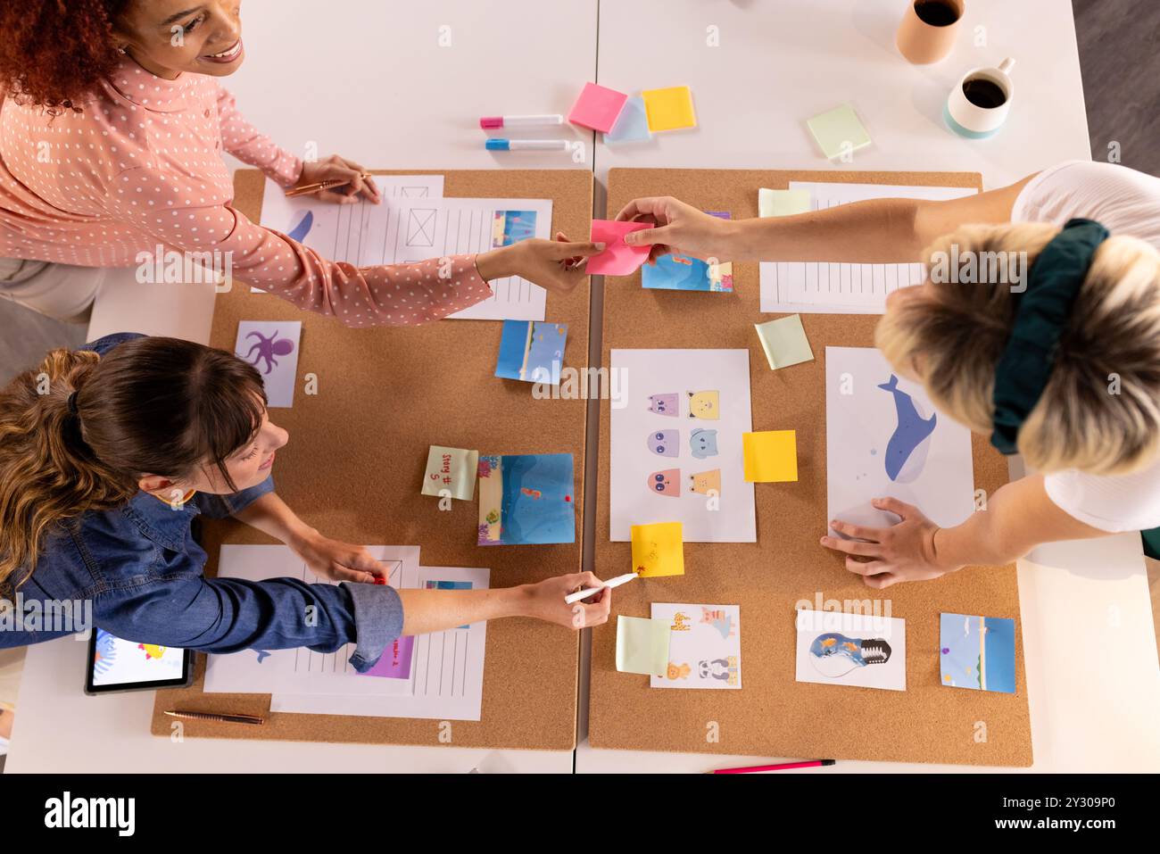 At office, collaborating on creative project, multiracial women using ...