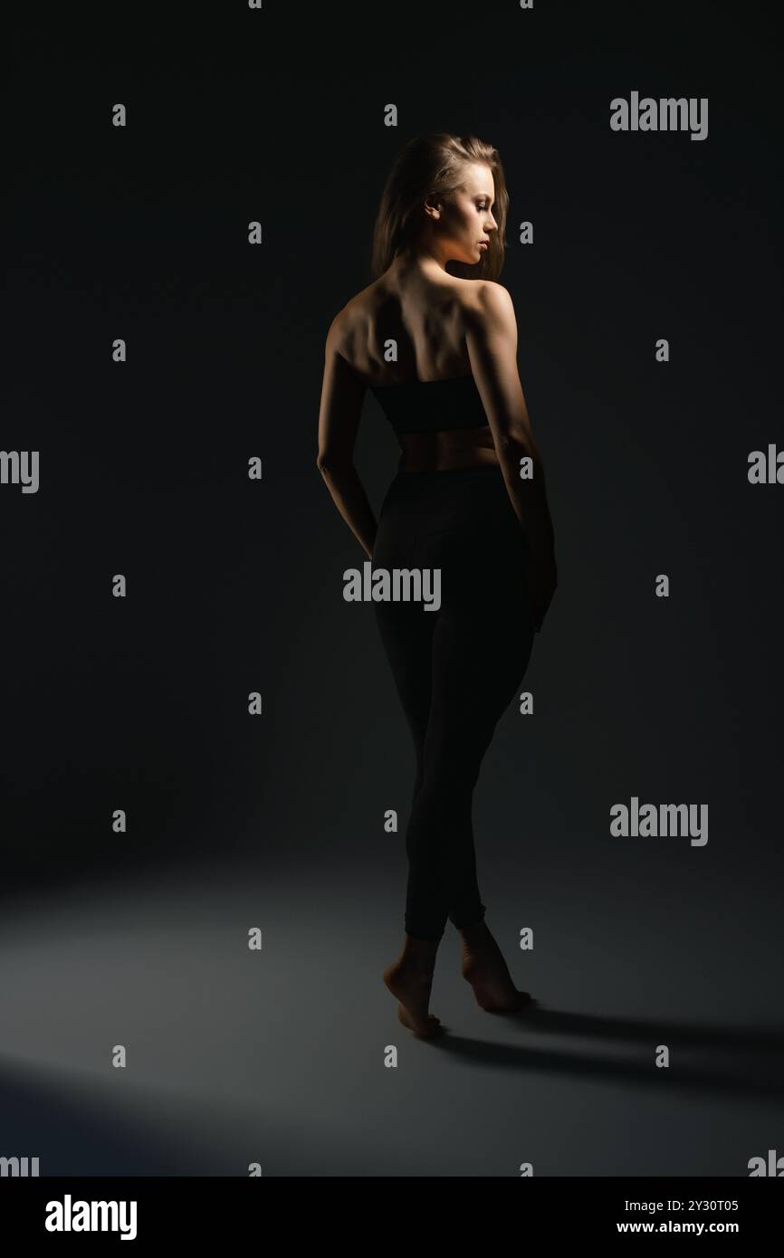 A model poses gracefully in a dimly lit studio during a photoshoot ...