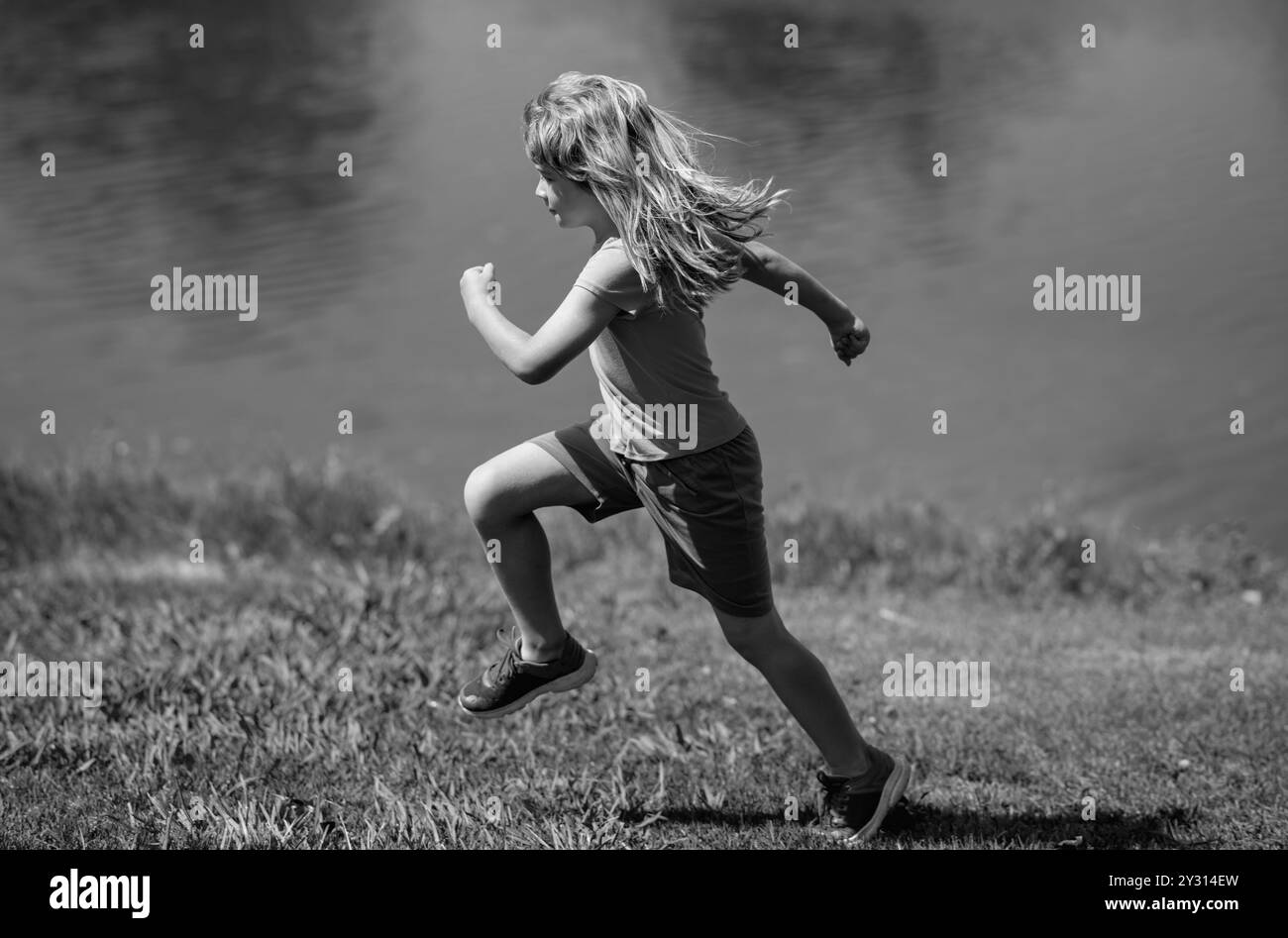 Kid boy running on green grass near lake in summer park. Child running ...