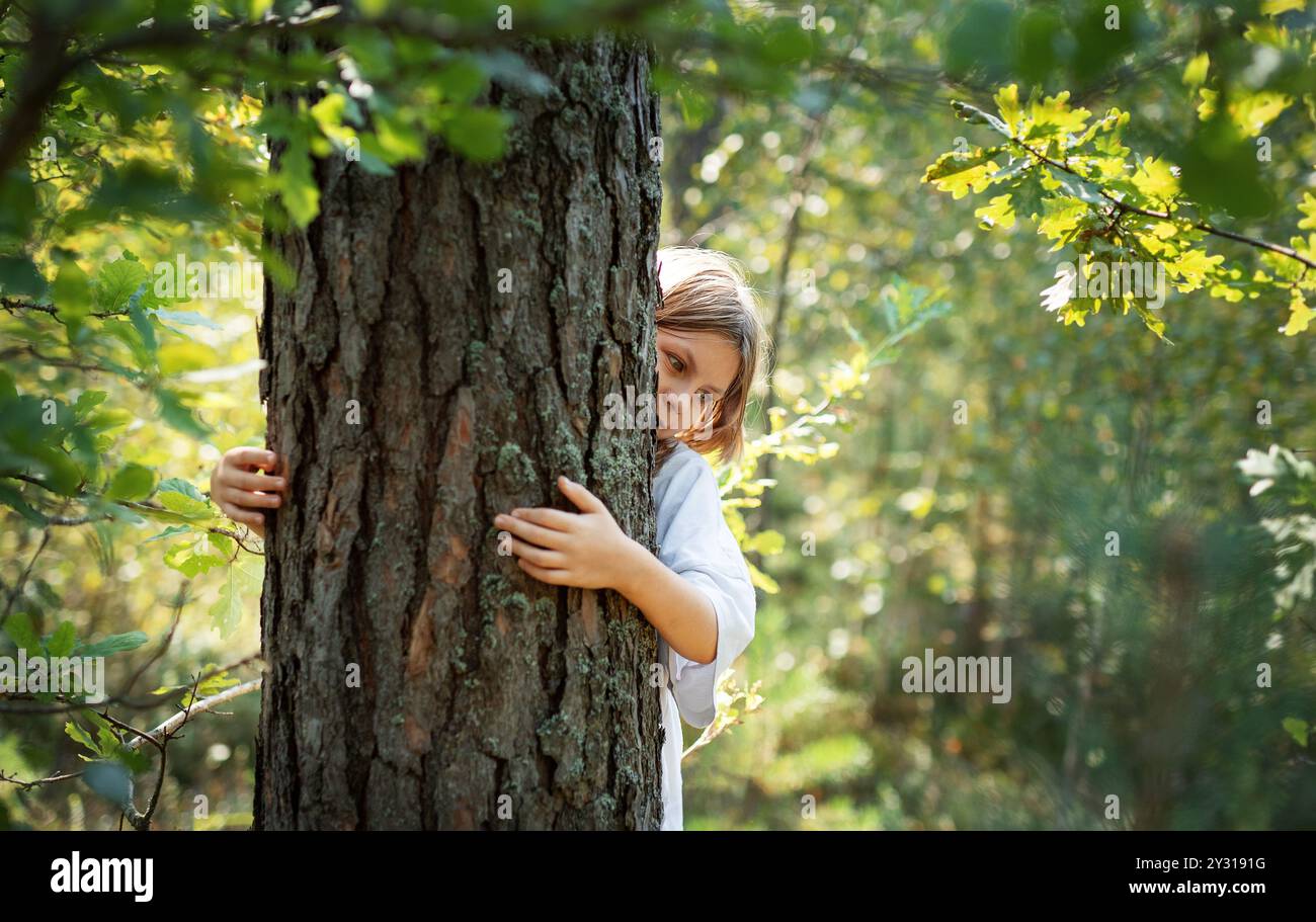 A teenage girl hugs a tree in the forest. Hugging and touching trees to ...