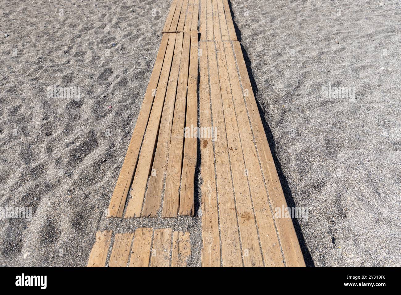 Empty wooden walkways lie on the beach sand on a sunny summer day ...